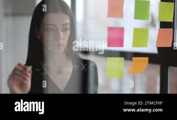 Attractive female manager writes down information and reminders on ...