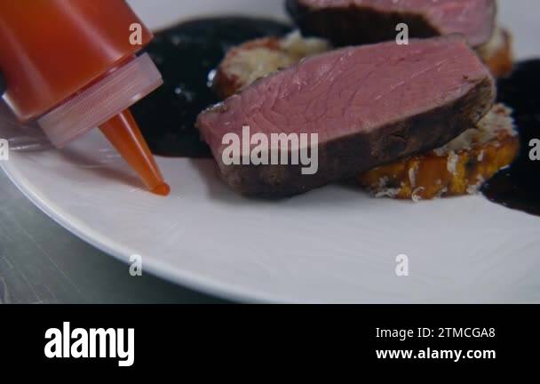 Chef makes dish presentation. The cook pours sauce on plate with roast ...