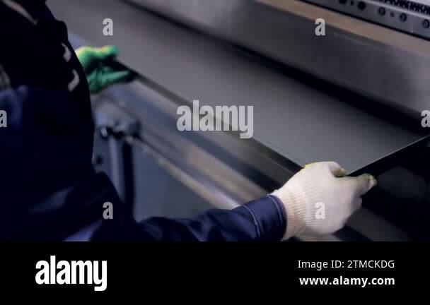 Worker hands bend metal sheet on a modern bending industrial machine at ...