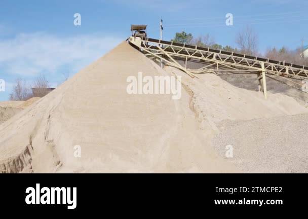 Large mounds of sifted sand at a cement factory. Heavy machines working ...