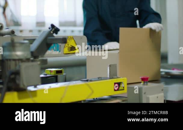 Closing a cardboard box on a conveyor belt line. Distribution warehouse ...