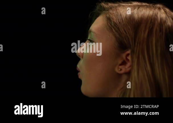 Side view face of talented girl singing out loud on stage in darkness ...