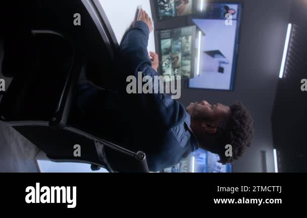 African American security officer works on PC, controls CCTV cameras in ...