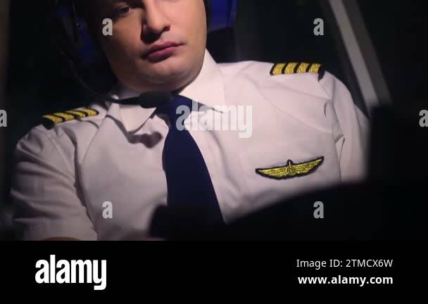 Serious male pilot in civil aviation uniform looking at flight control ...