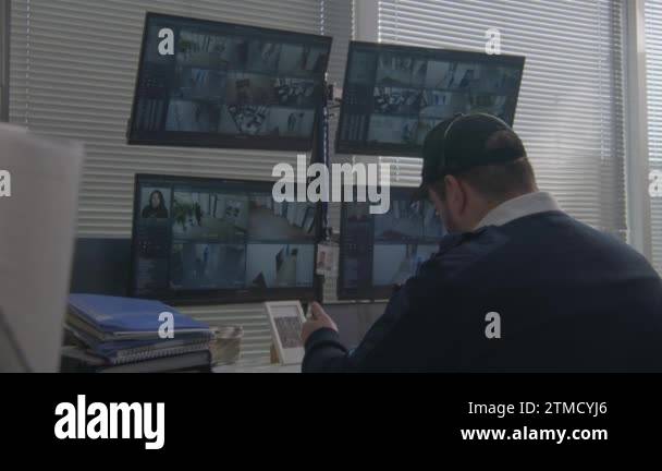 Security guard monitors CCTV cameras on computers and digital tablet ...
