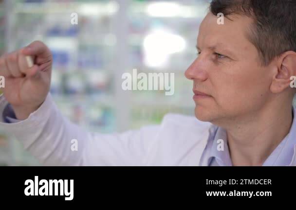 Side view headshot of focused man looking at pill in hand indoors ...