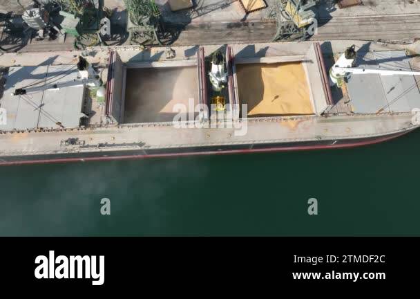 Loading dry cargo ship of wheat by cranes in port. Aerial view loading into holds of sea cargo ...