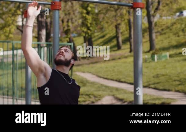 Athletic lebanese man in sportswear doing pull ups exercises on horizontal bar. Young guy ...