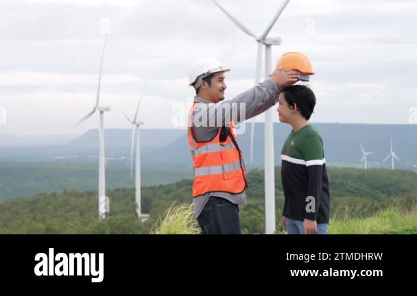 Engineer with his son on a wind farm atop a hill or mountain in the ...