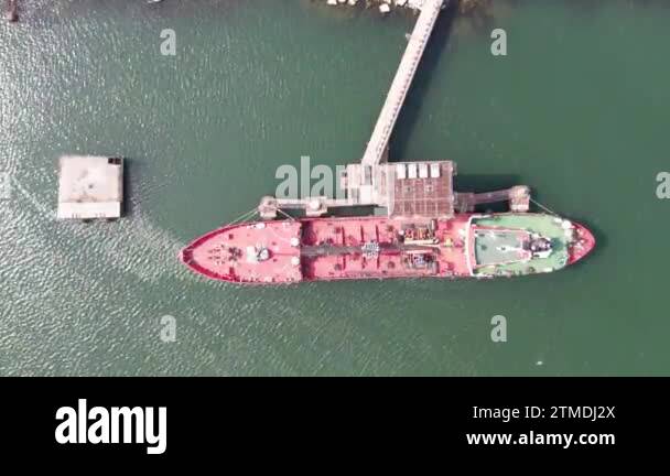 Red tanker ship loading and unloading oil and gas storage at industrial ...