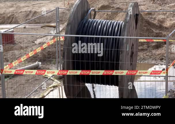 High voltage cable reel in wet sand and road construction workers ...