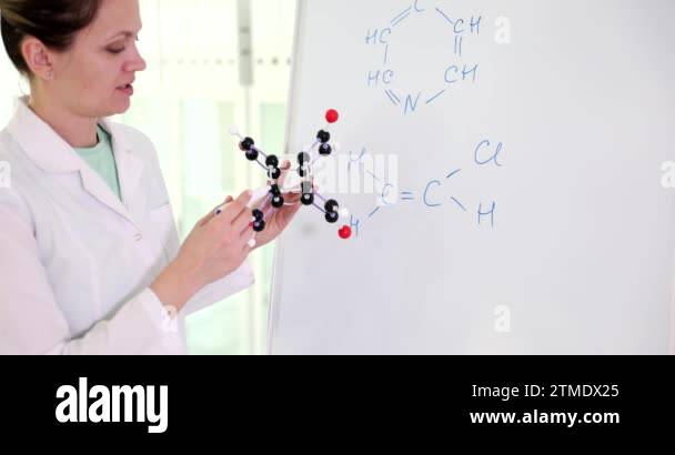Serious woman examines molecules of chemical compounds holding model in ...