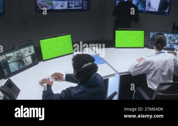 Multi ethnic officers and operators control CCTV cameras. Employees ...