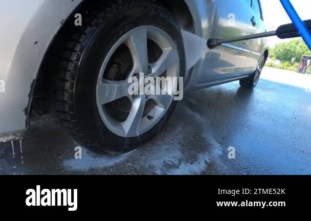 Mechanical washing of the rear wheels of the car from a hose at a car ...