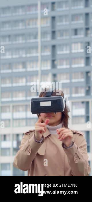 Teenage girl wearing VR glasses, immersed in a virtual world, while gesturing in front of ...