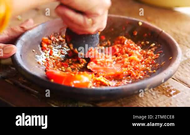 Making sambal with mortal and pestle. Sambal is Sambal is an Indonesian ...