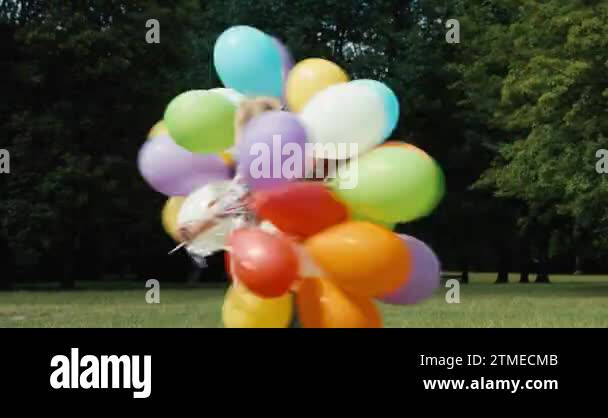 Girl jumping with balloons and spinning and laughing at camera Stock ...