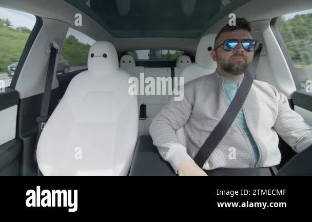 Mature male driver inside Tesla Model Y car using self drive autopilot ...