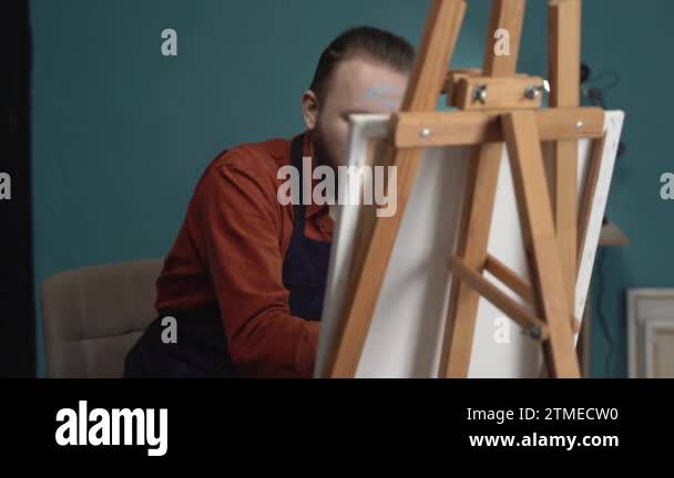 portrait of a bearded millennial artist working in an apron while ...