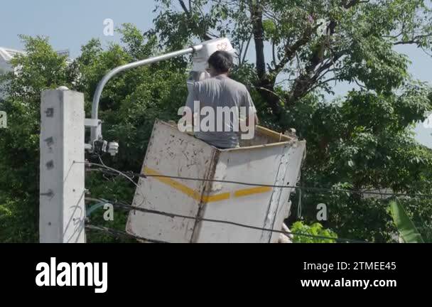 Worker on height lifting platform installing new street light bulb ...