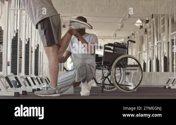 Tilt up of professional African American physiotherapist helping male ...