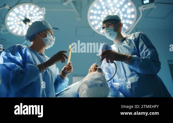 Nurse and young surgeon with surgical headlight and in safety goggles ...