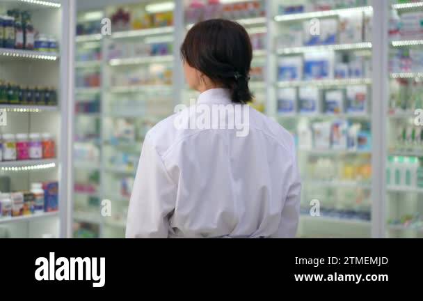 Back view thoughtful woman standing in pharmacy turning looking around ...