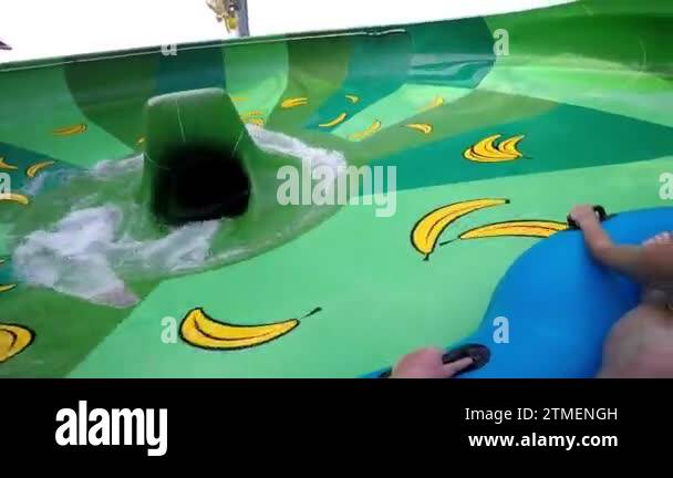 Happy man and woman riding down the water slide. People having fun in ...