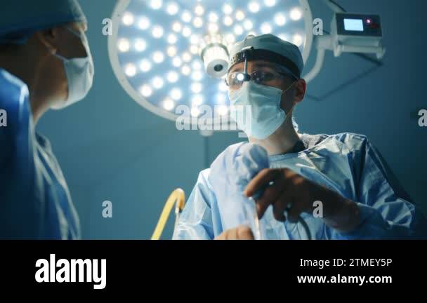 Over the shoulder shot of surgeon and nurse during plastic surgery ...