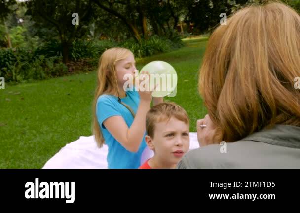 A mother blows up a balloon for her youngest son - arch shot Stock ...