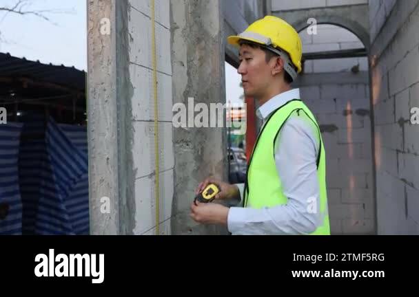 Young Asian engineer in engineering uniform and helmet at construction ...