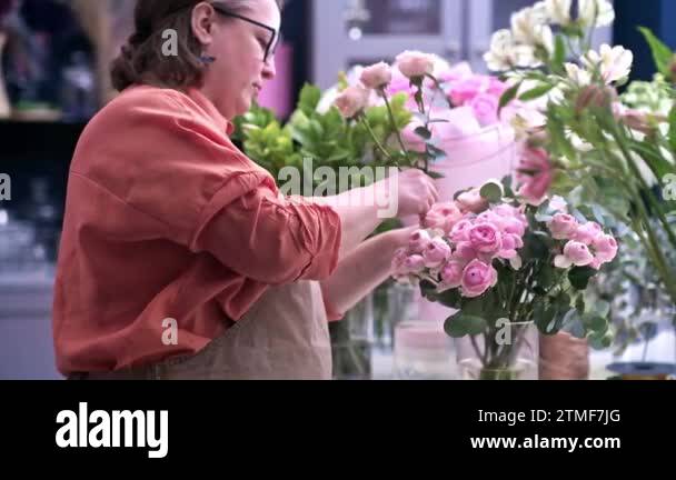 The skilled female florist and business owner expertly arranges a ...