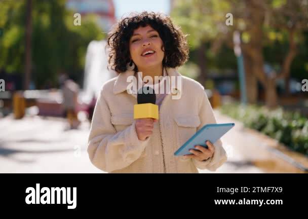 Young hispanic woman news reporter speaking using microphone and ...