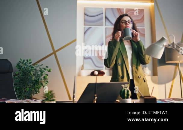 Successful young business woman chatting smartphone drinking tasty tea ...