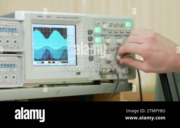 Mens engineering arm adjusts the oscilloscope for proper display of the ...