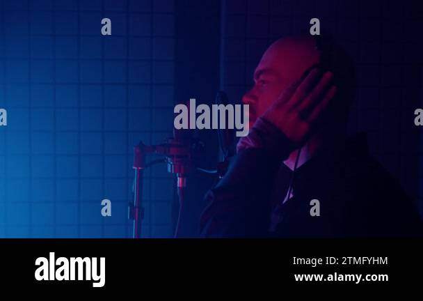 handsome bald singer is performing song in isolation booth of recording ...