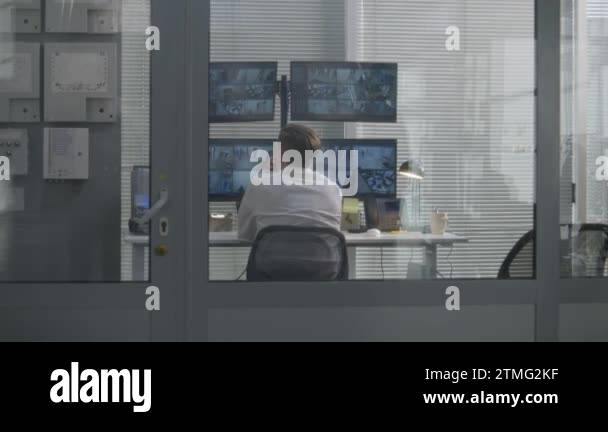 Security operator monitors office CCTV cameras on computers, uses ...