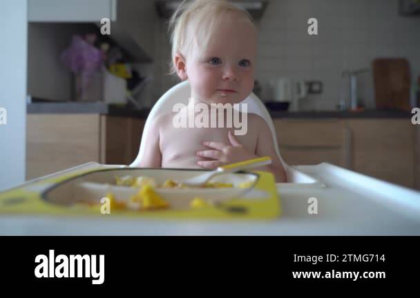 Funny little girl baby eats with her hands eating by her own laughing ...