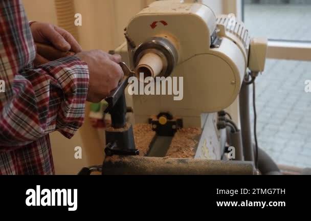 Man carpenter using chisel for shaping piece of wood on turning lathe ...