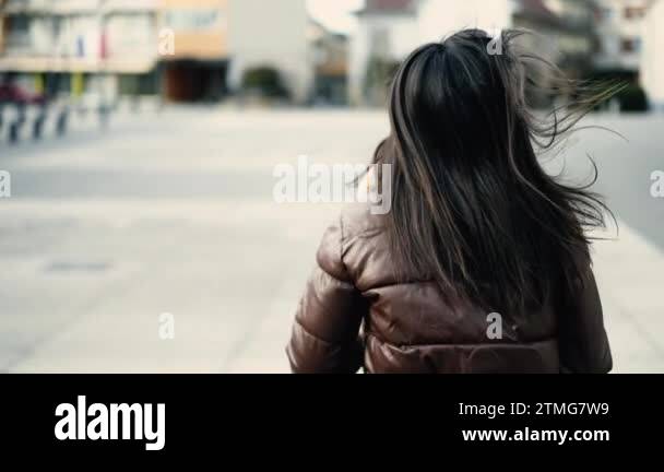 Back of Carefree young woman with long hair running outside in slow ...