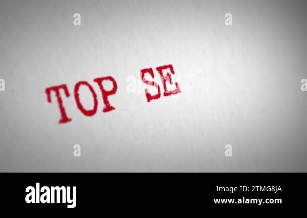 Manual typewriter types the words Top Secret - Classified in red ink ...