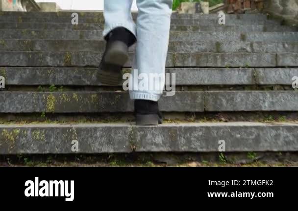 Woman legs in jeans walking on ancient stair back view. Female foot in ...