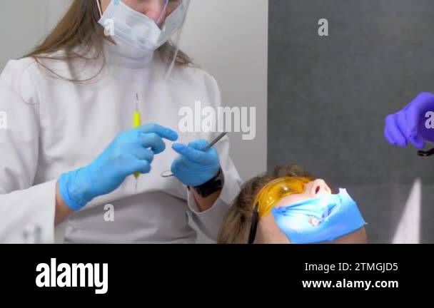 Tooth restoration with filling and polymerization lamp. Young girl ...