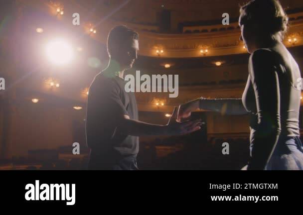 Ballerina with partner stands on theater stage and discusses preparing ...