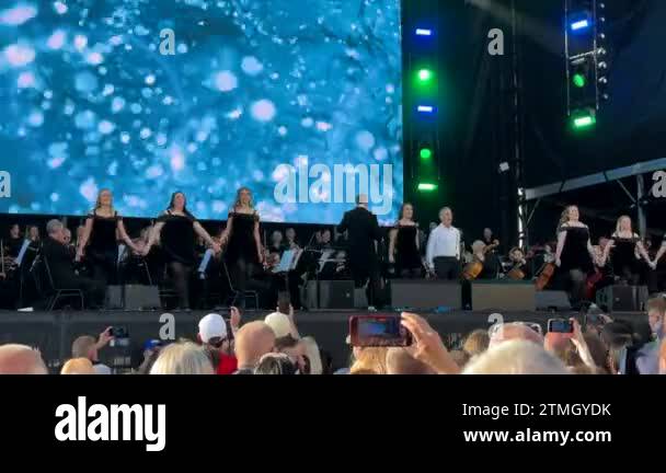 Women line dance and one man group and orchestra performing on big ...