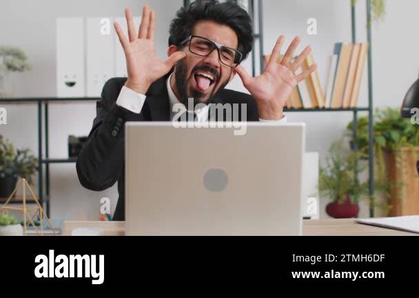 Indian businessman hiding behind laptop computer, making funny face ...