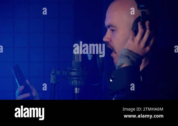Slow motion shot of a young rapper recording a track in audio studio ...
