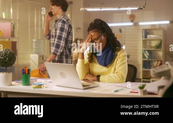 A young African American woman is typing on a laptop keyboard and is ...