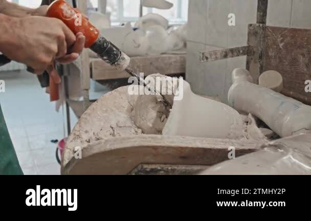 Unrecognizable craftsman removing plaster from prosthetic leg socket after casting it in modern ...