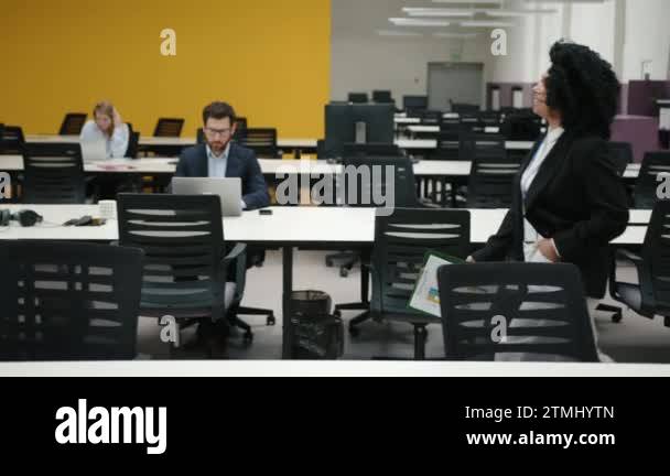 Cheerful African American employee strolling in modern office space ...